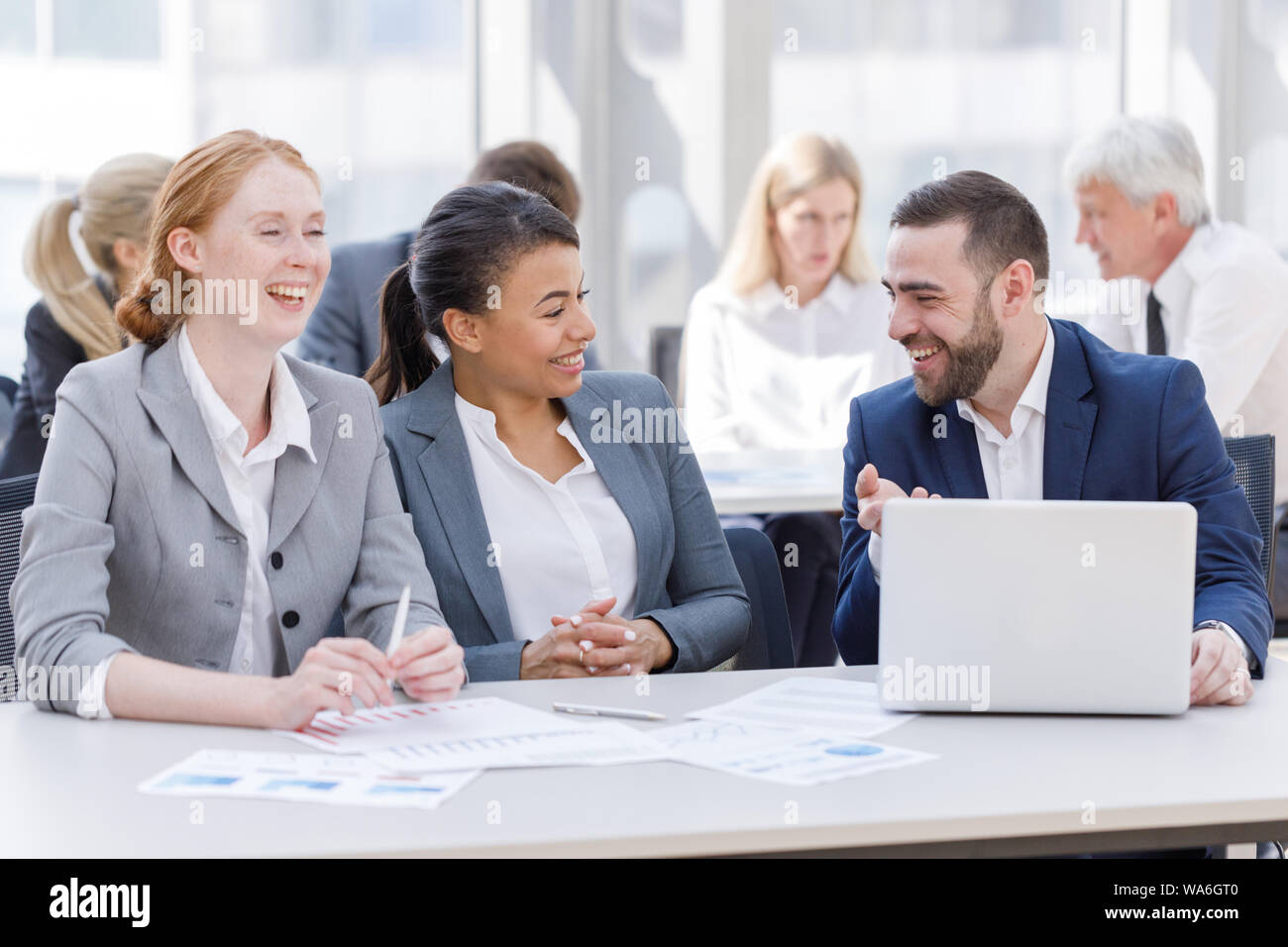 Business team sitting by the table with laptop and documents in office ...