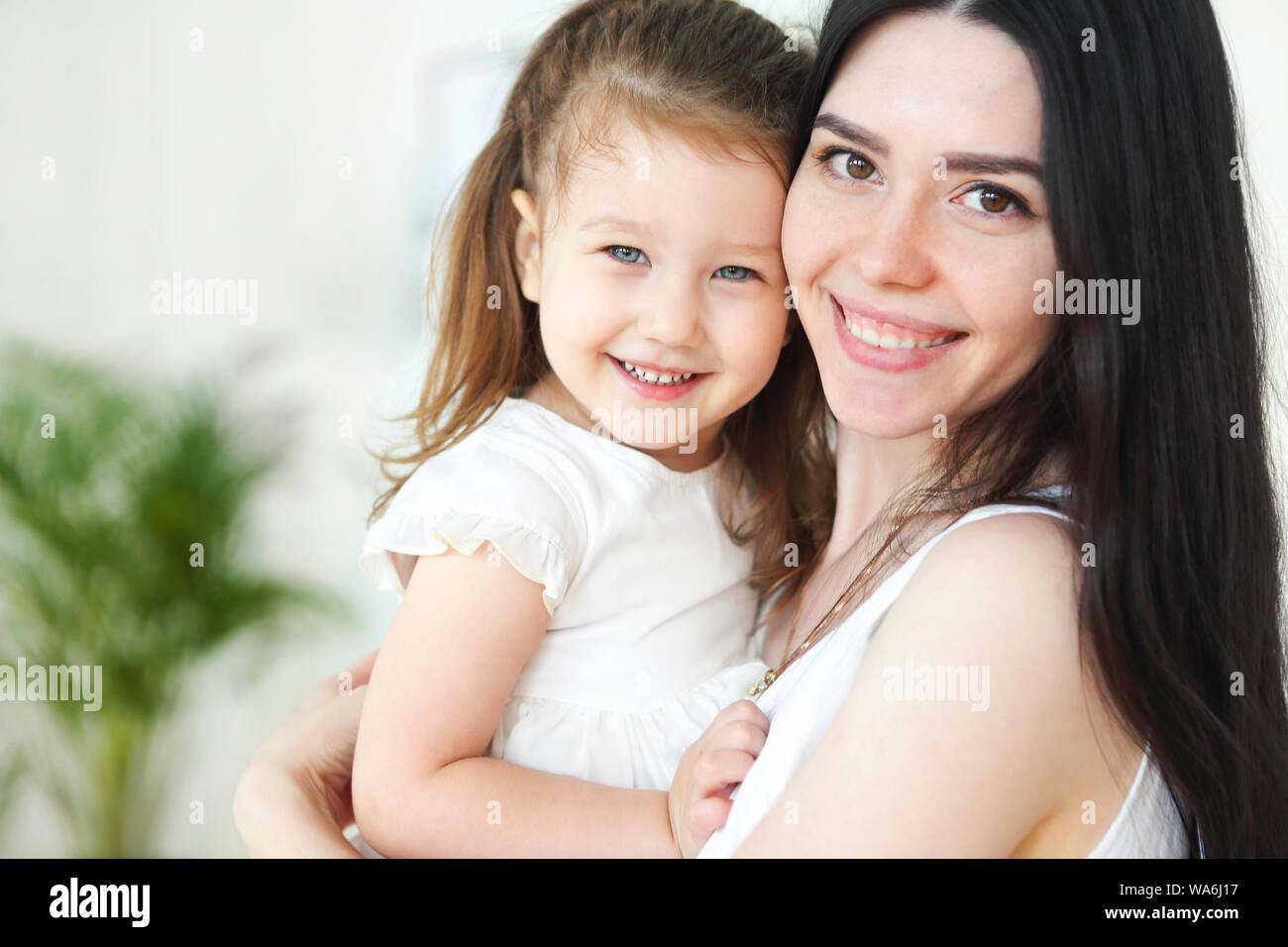 Happy young bright mother hugging her little daughter having fun ...