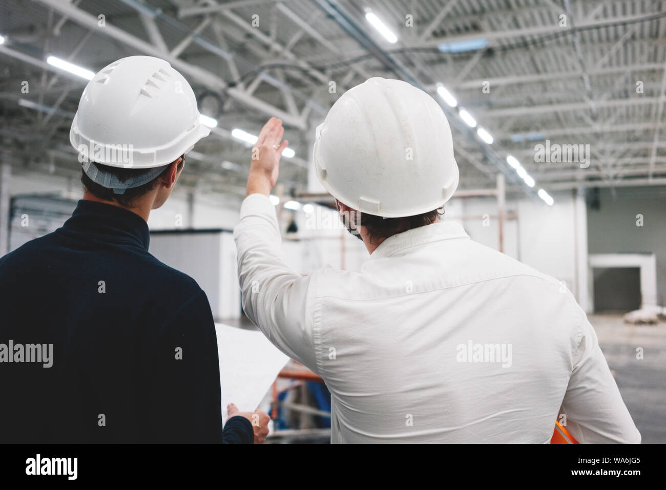 Two building engineers wearing safety hard hat discussing blueprint on ...