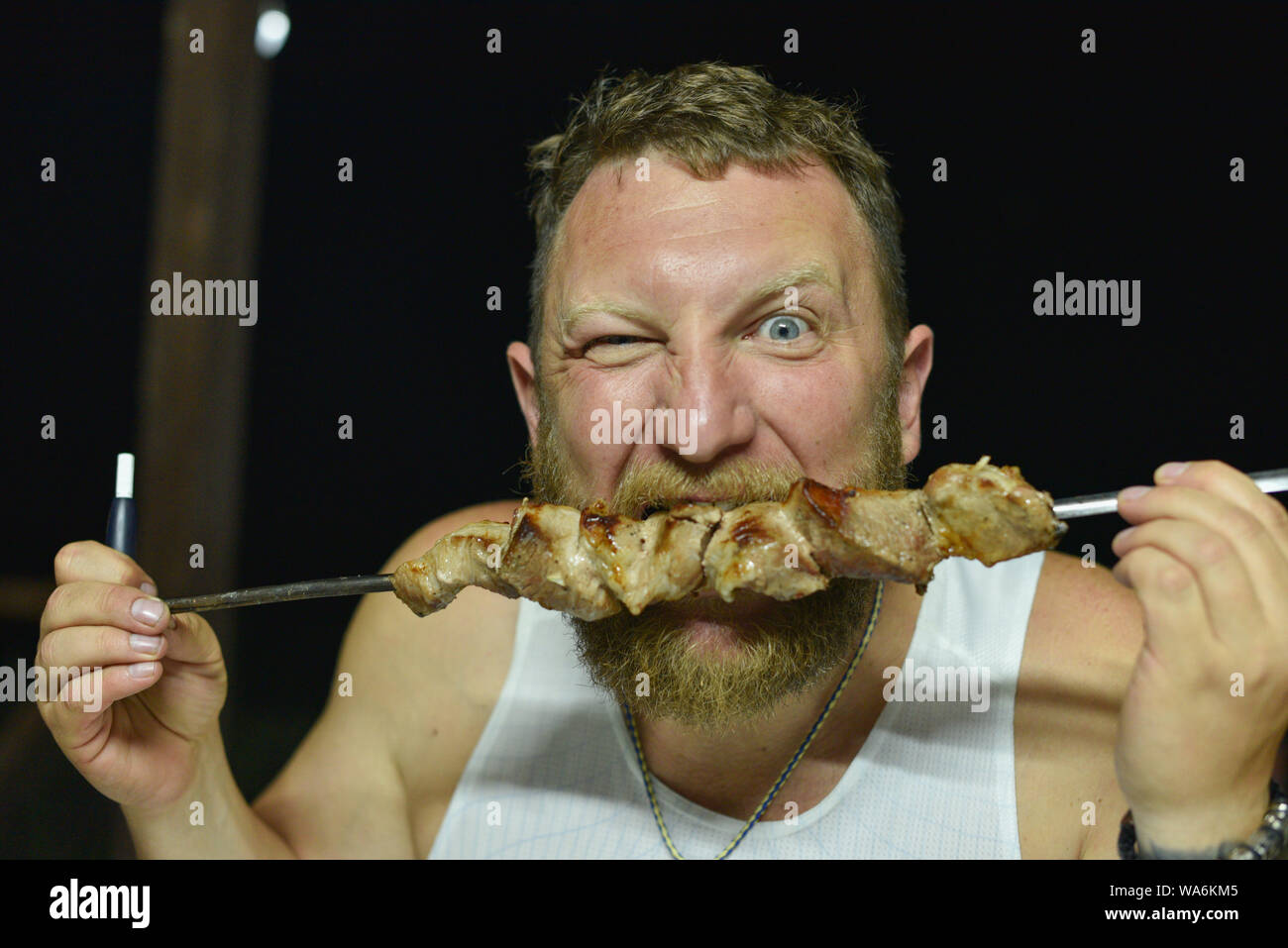 Bearded man eats delicious barbecue. A man with a red beard eats ...