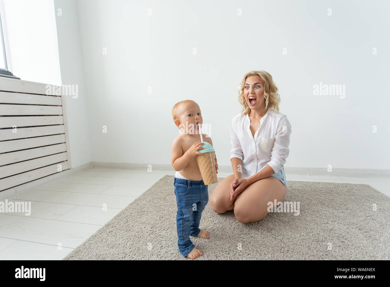 family, child and parenthood concept - happy smiling young mother playing with little baby at ...