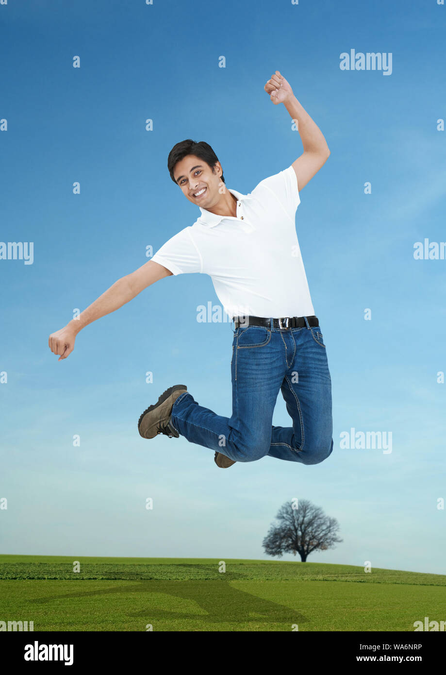 Young man jumping in air and smiling Stock Photo - Alamy