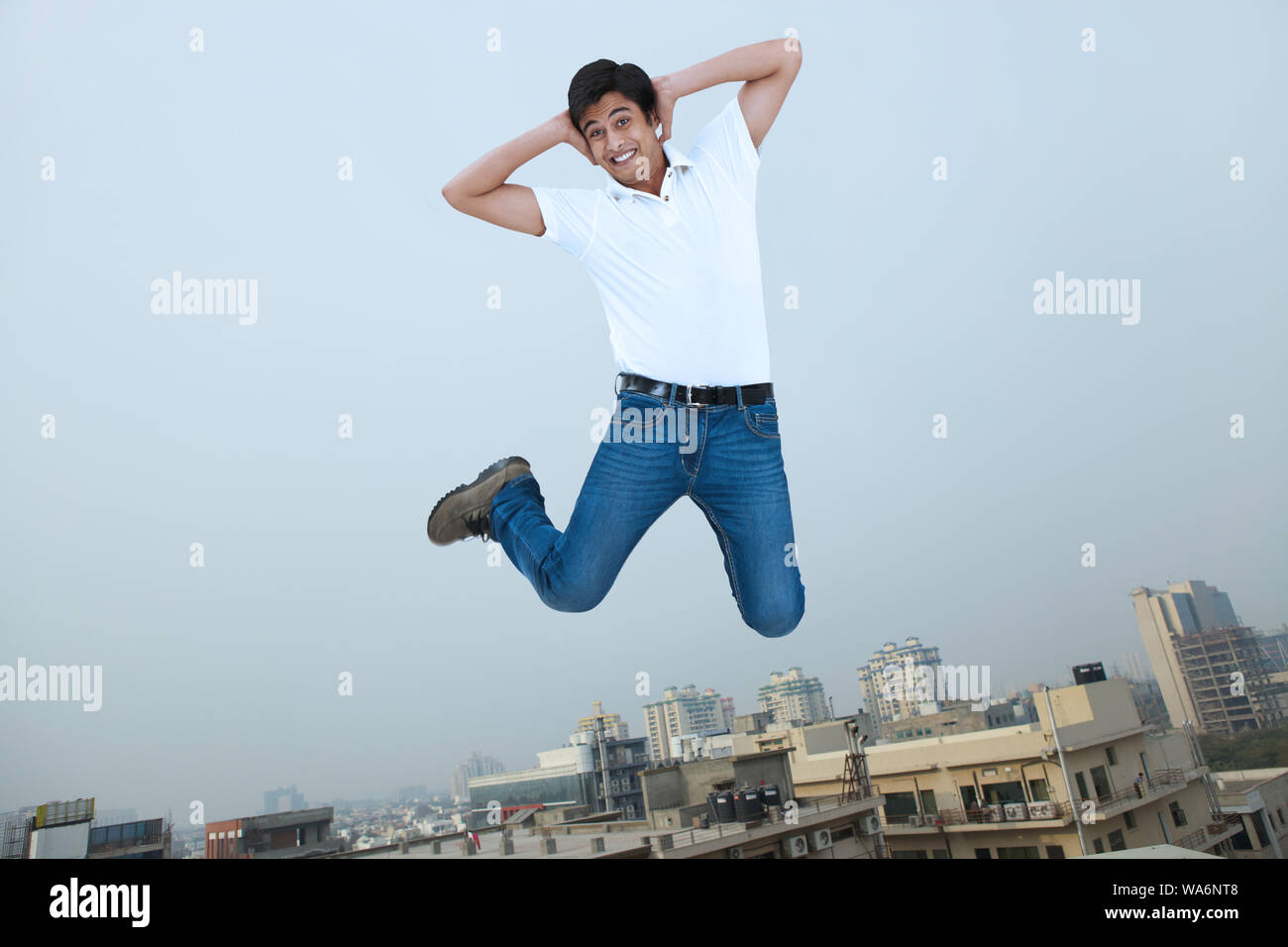 Young man jumping in air and smiling Stock Photo - Alamy