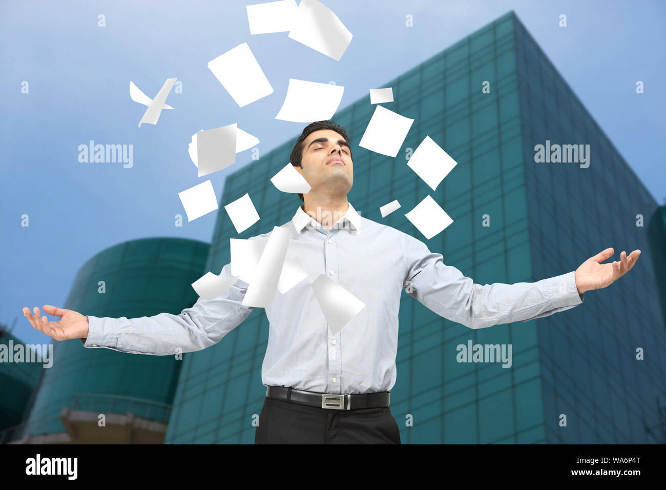 Papers falling on a businessman standing with his arms outstretched ...