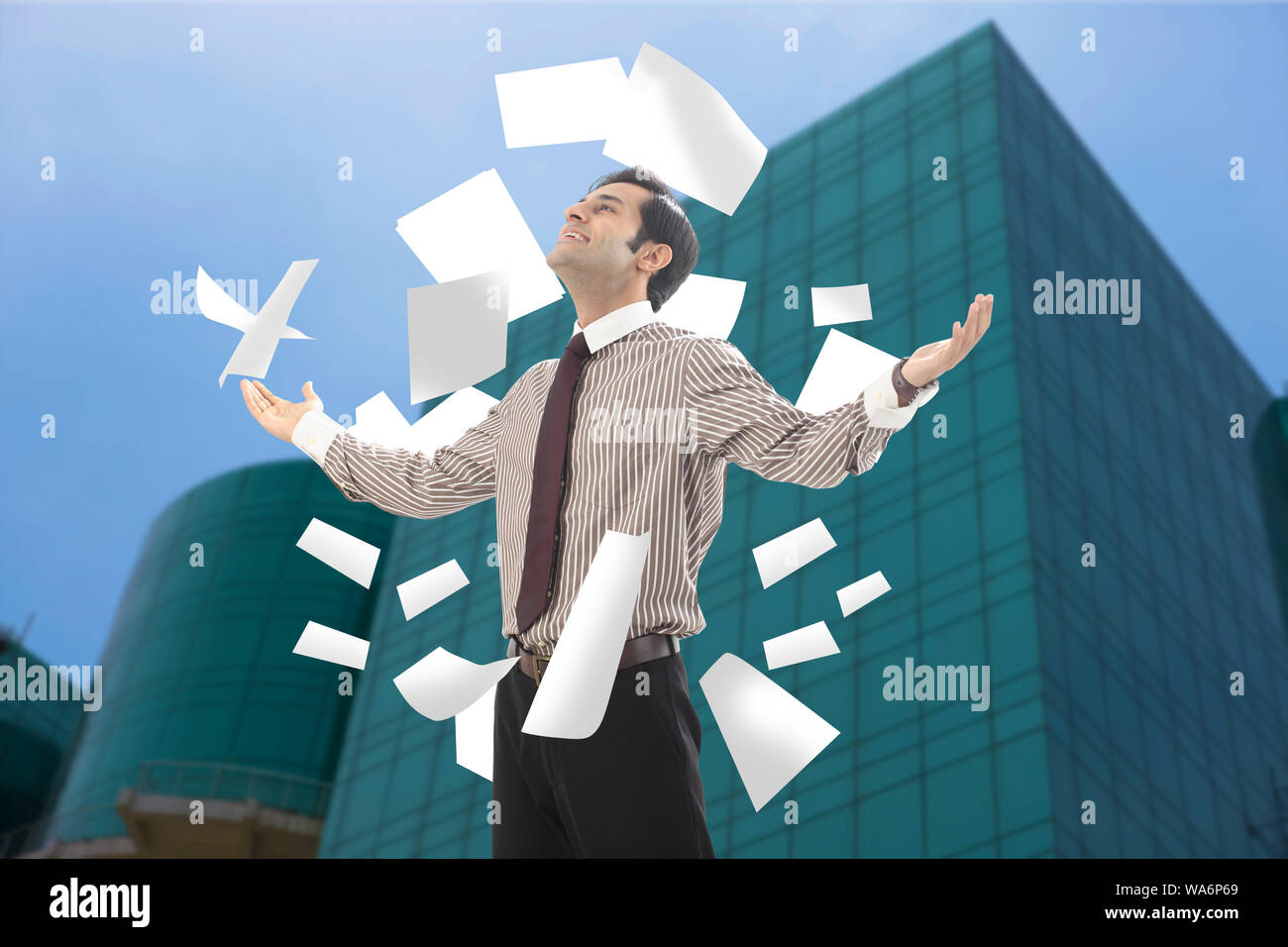 Papers falling on a businessman standing with his arms outstretched ...