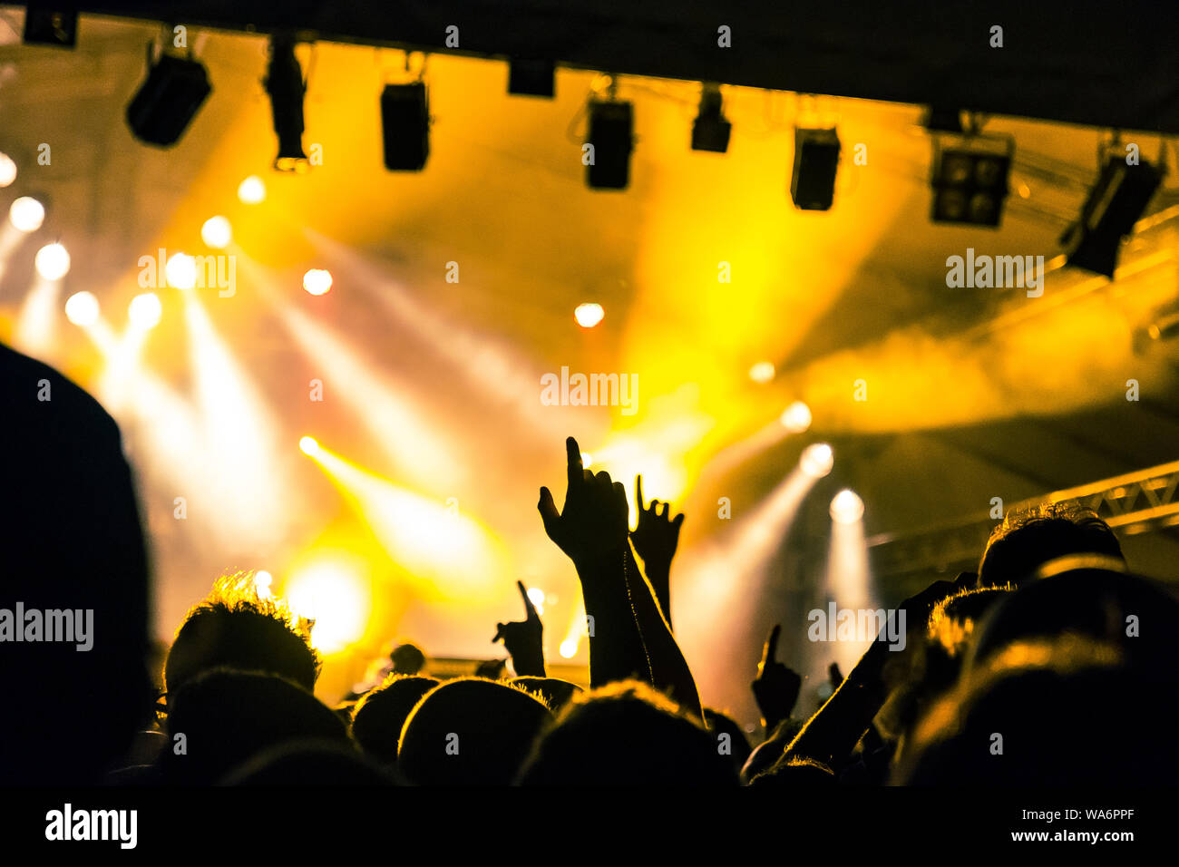 Concert crowd in front of a brightly lit stage; in the background ...
