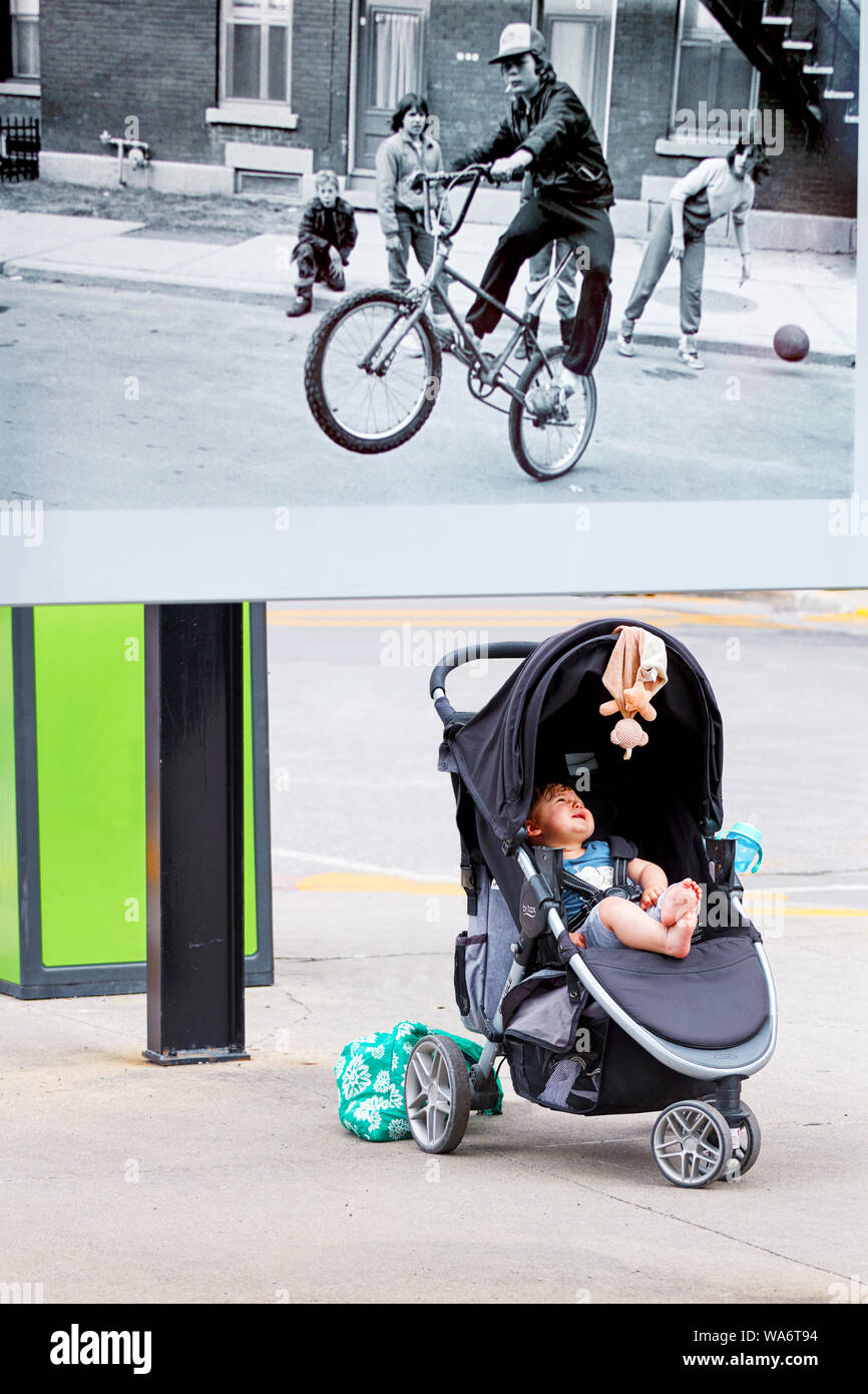 Baby in a stroller under the nostalgic billboard photo of old ...