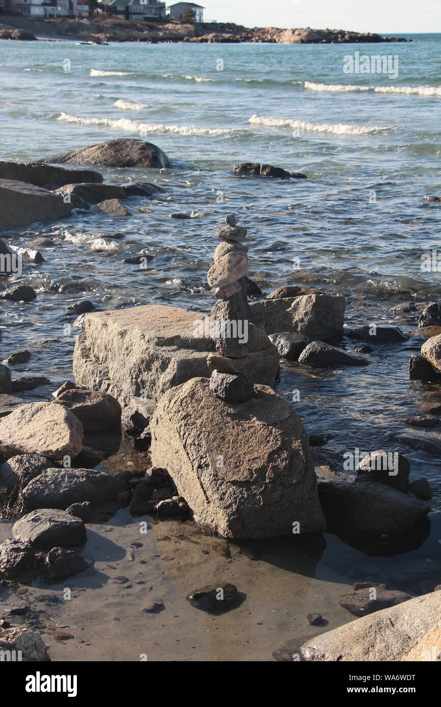 rocks stacked in zen pile at ocean with rolling waves in background ...