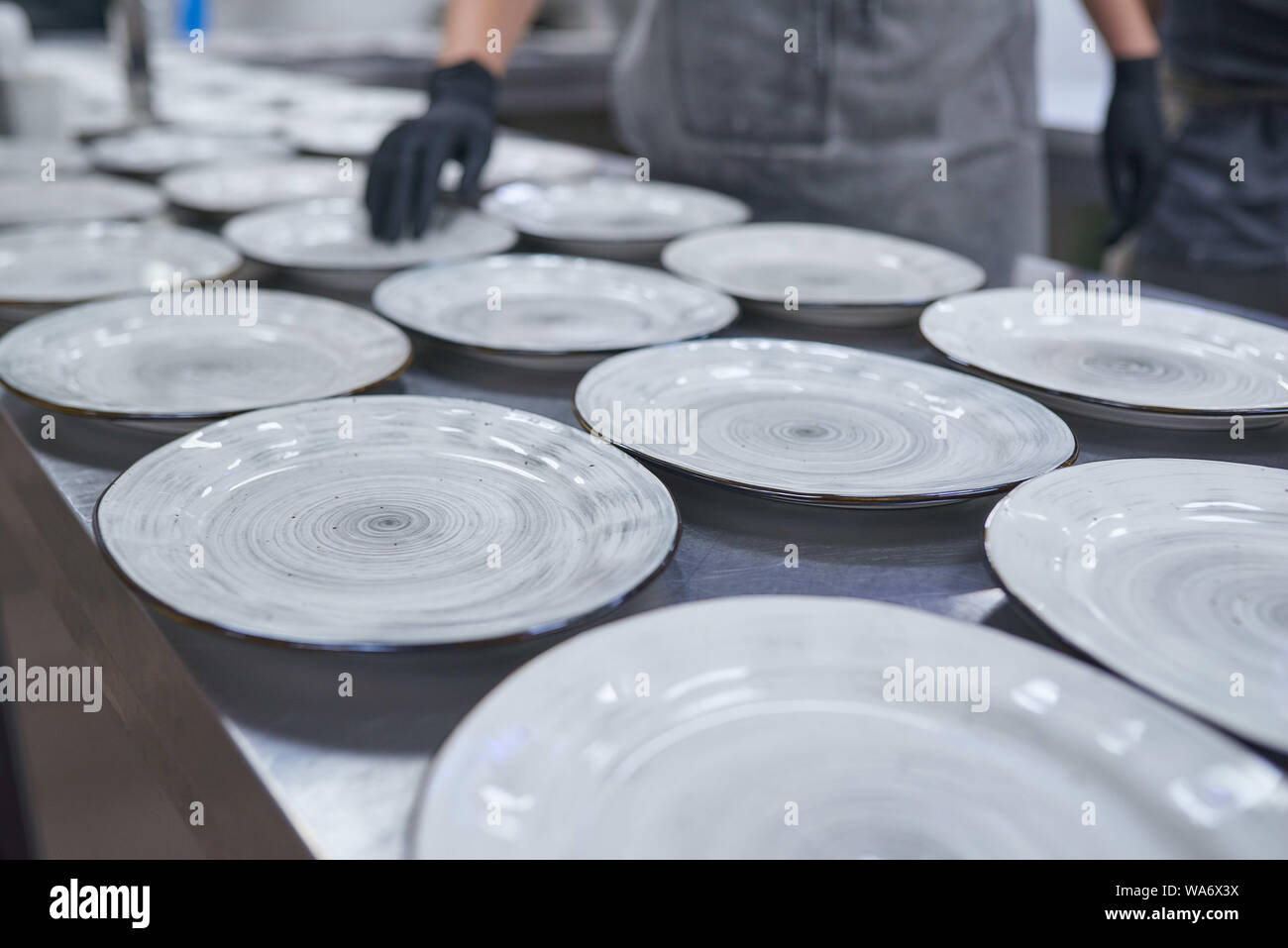 Many empty plates on a table in a restaurant kitchen stand one after ...