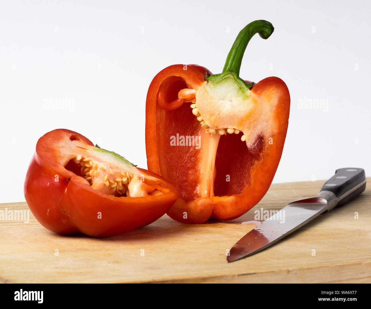 A red (bell) pepper cut in half on a chopping board, with knife Stock ...
