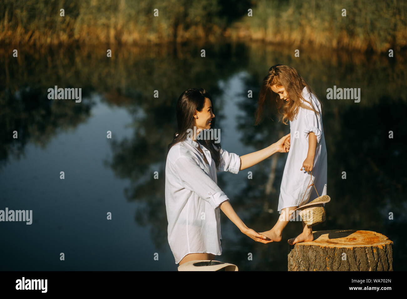 Mother and daughter playing and having fun on stump on background of ...
