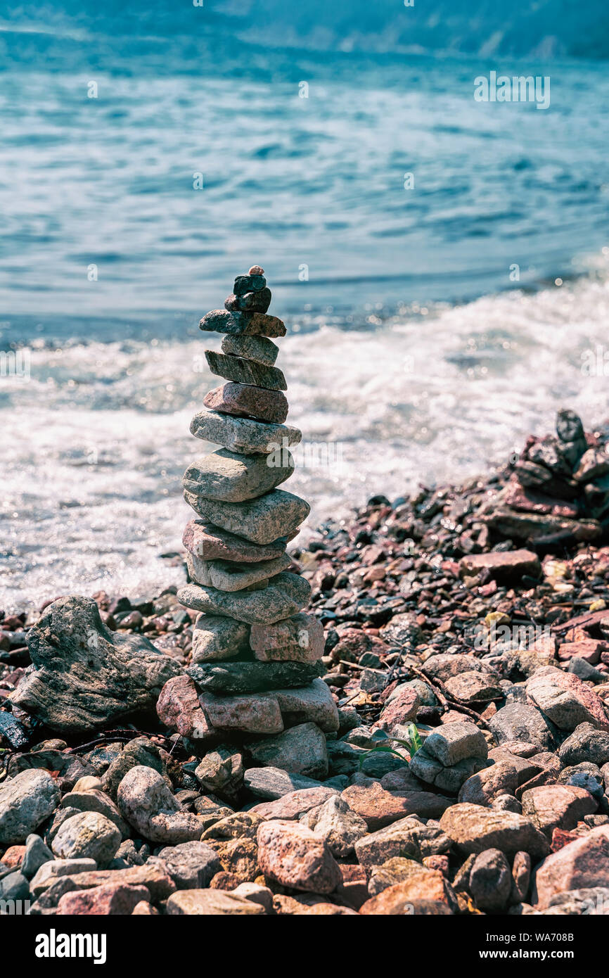 Pyramid of pebbles on the beach on a background of the sea wave ...