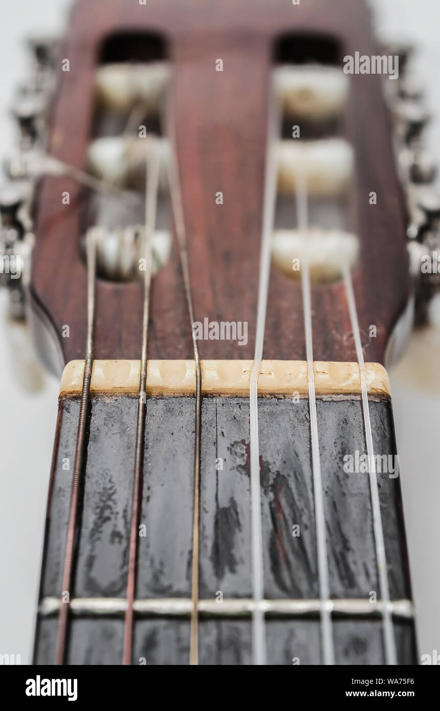 Focus on the nut and strings of a acoustic guitar headstock. Old ...