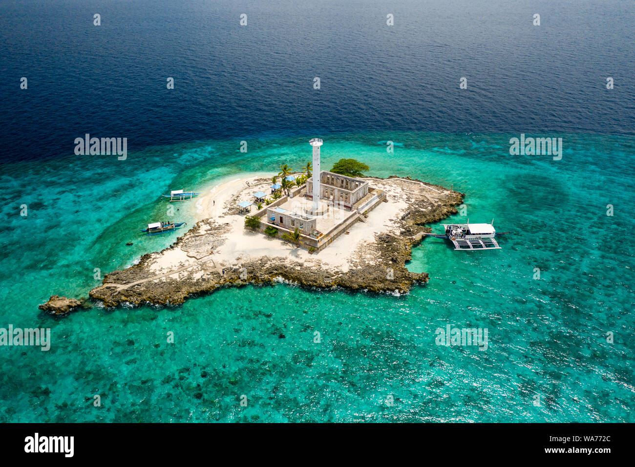Aerial drone view of traditional boats next to a tiny tropical island ...