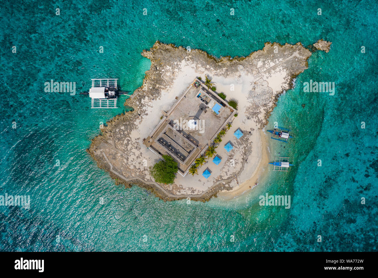 Aerial drone view of traditional boats next to a tiny tropical island ...