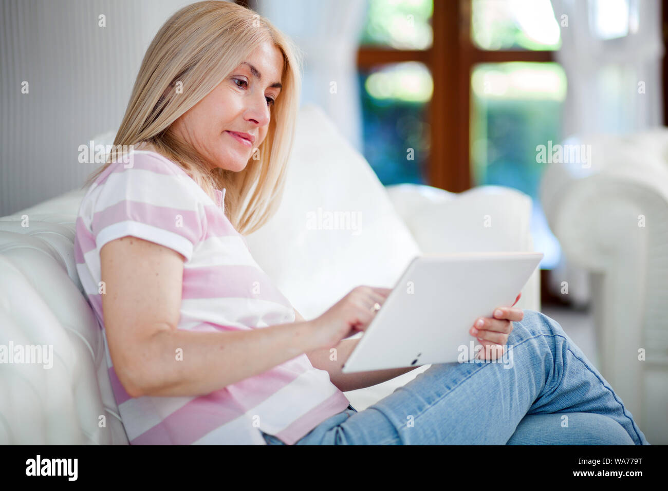 Beautiful mature woman using electronic tablet at home Stock Photo - Alamy