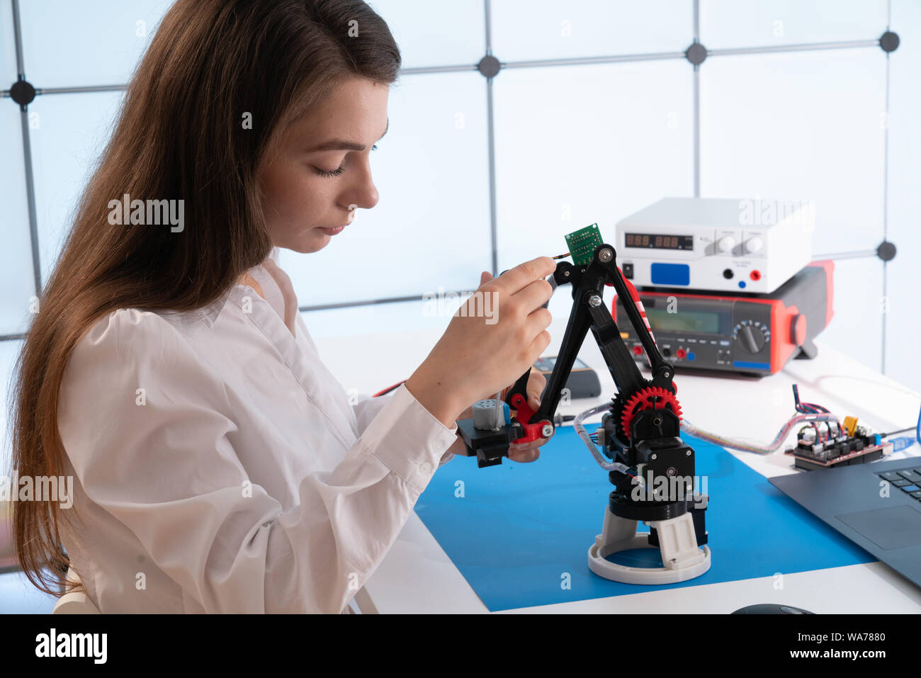 A young woman writes an algorithm for the robot arm. Science Research ...