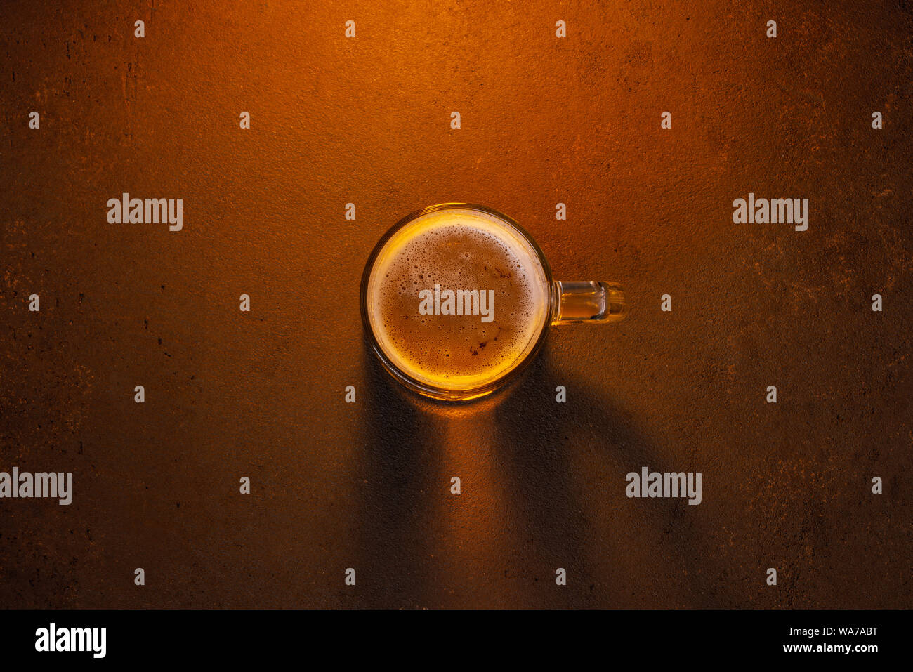 Beer mug on the brown textured table, ray of light through beer, top ...