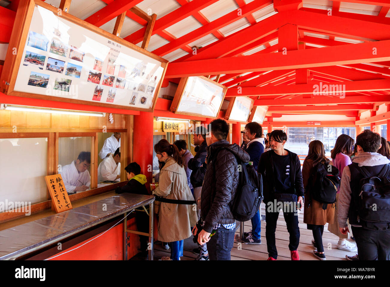 Japan, Miyajima. Itsukushima Shrine. Interior of shrine. People queuing ...