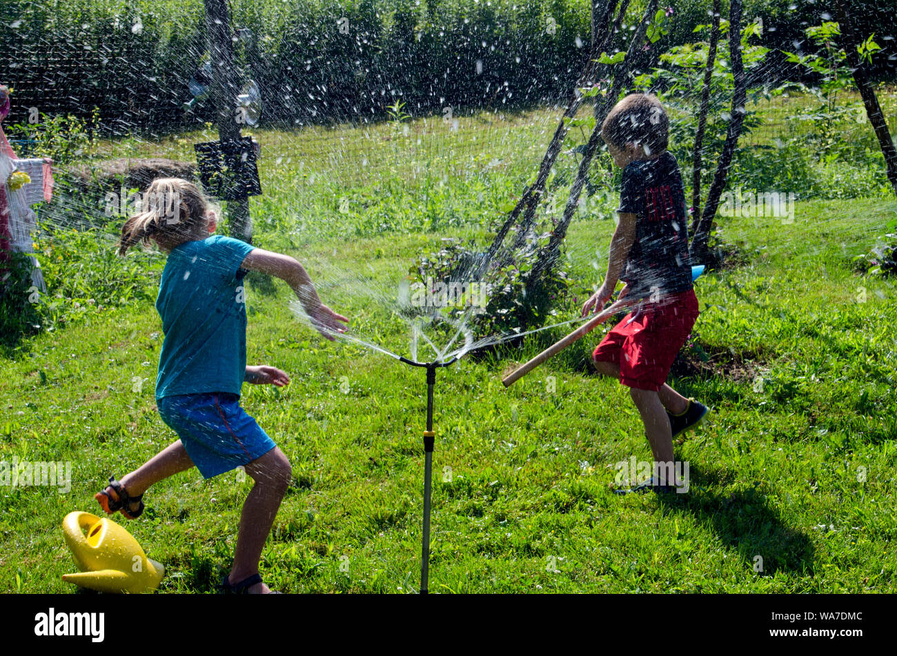 Two kids playing water sprinkler hi-res stock photography and images ...
