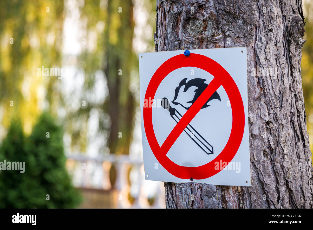 No match fire sign. Red circle with crossed match. Blurred park nature ...