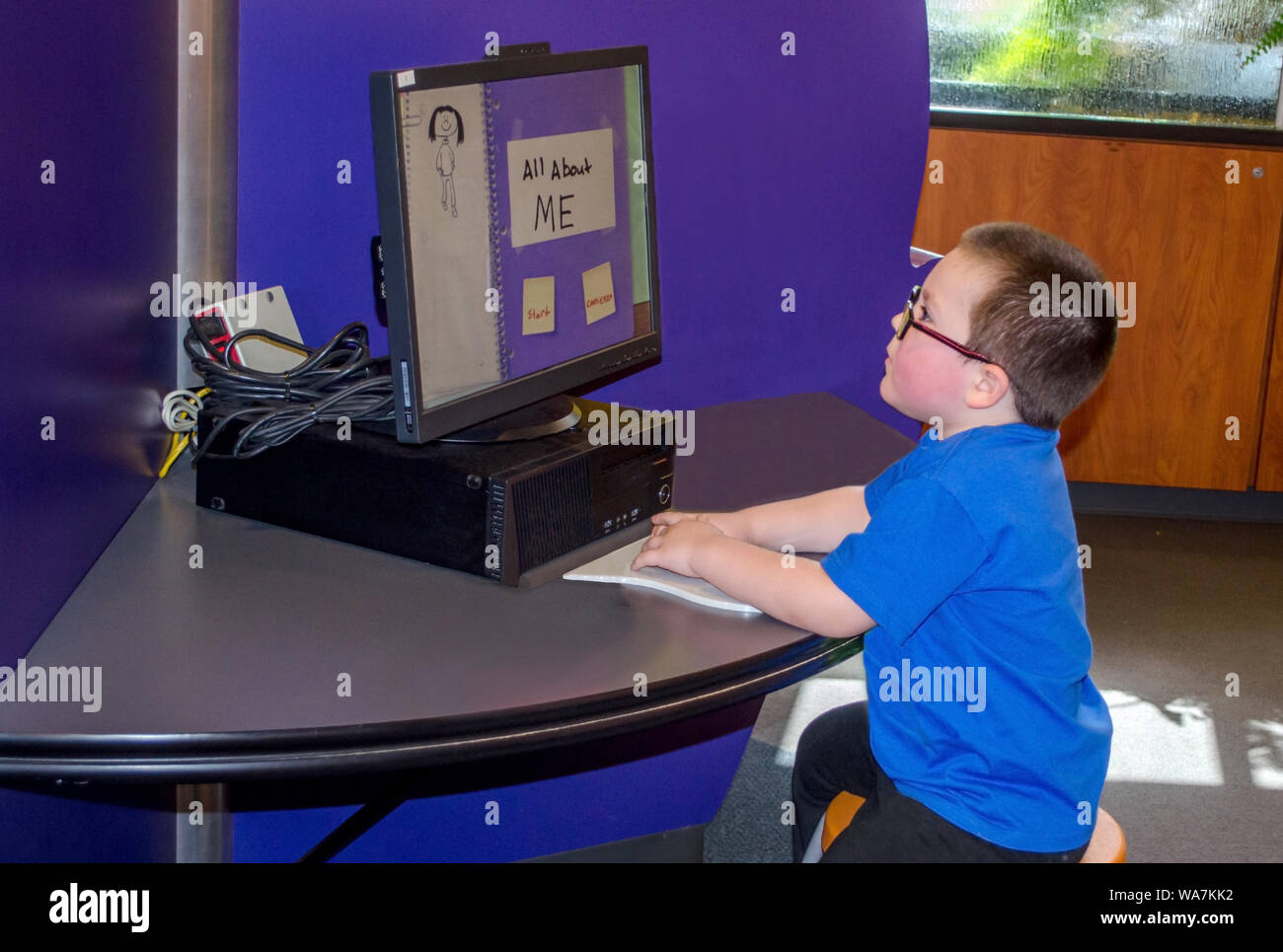 a little boy plays at a computer at a learning center, learning all ...