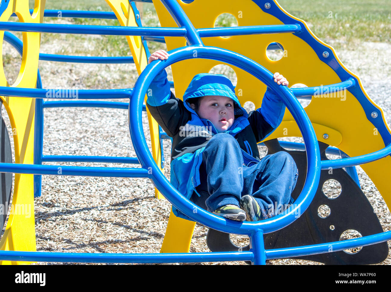 An active little boy climbs into a circle on the playground but looks ...