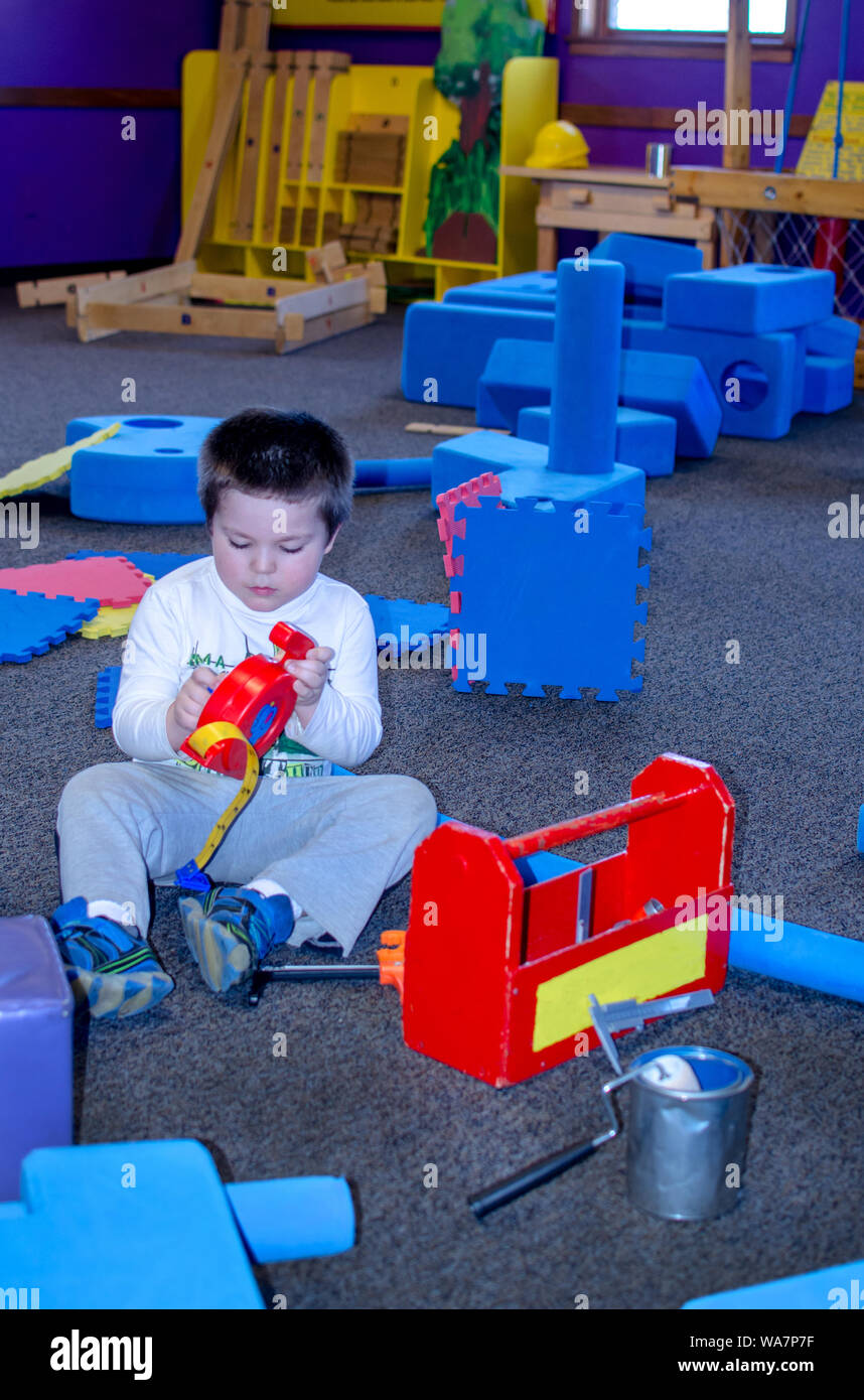 an active little boy builds with toy tools and big foam blocks Stock ...
