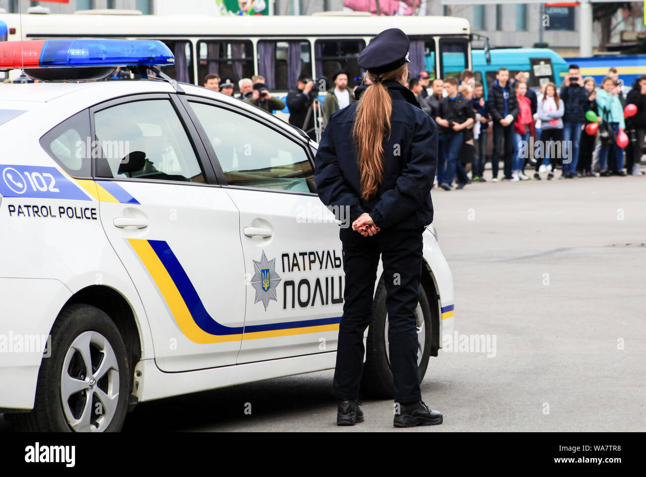 A girl is a police officer standing near a patrol police car with an ...