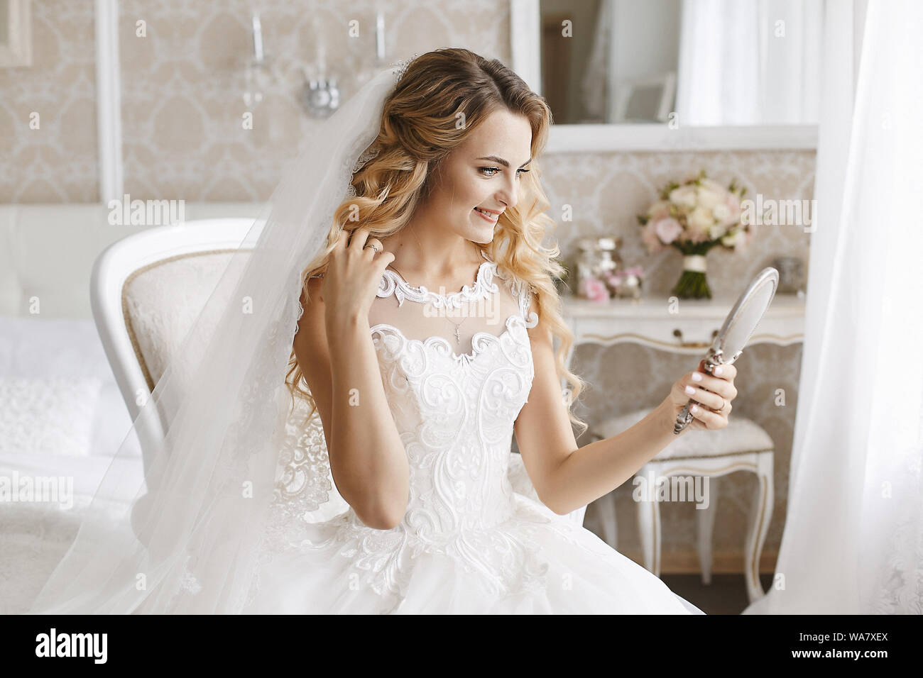 Beautiful bride in luxury wedding dress keeping the mirror and looking ...