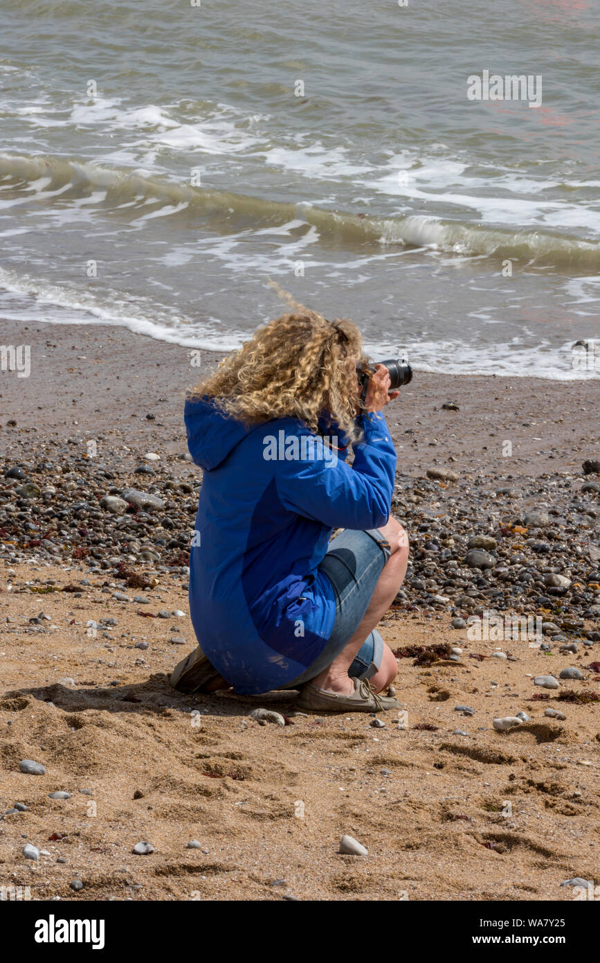 a woman or lady female crouching down on her haunches at the seaside ...