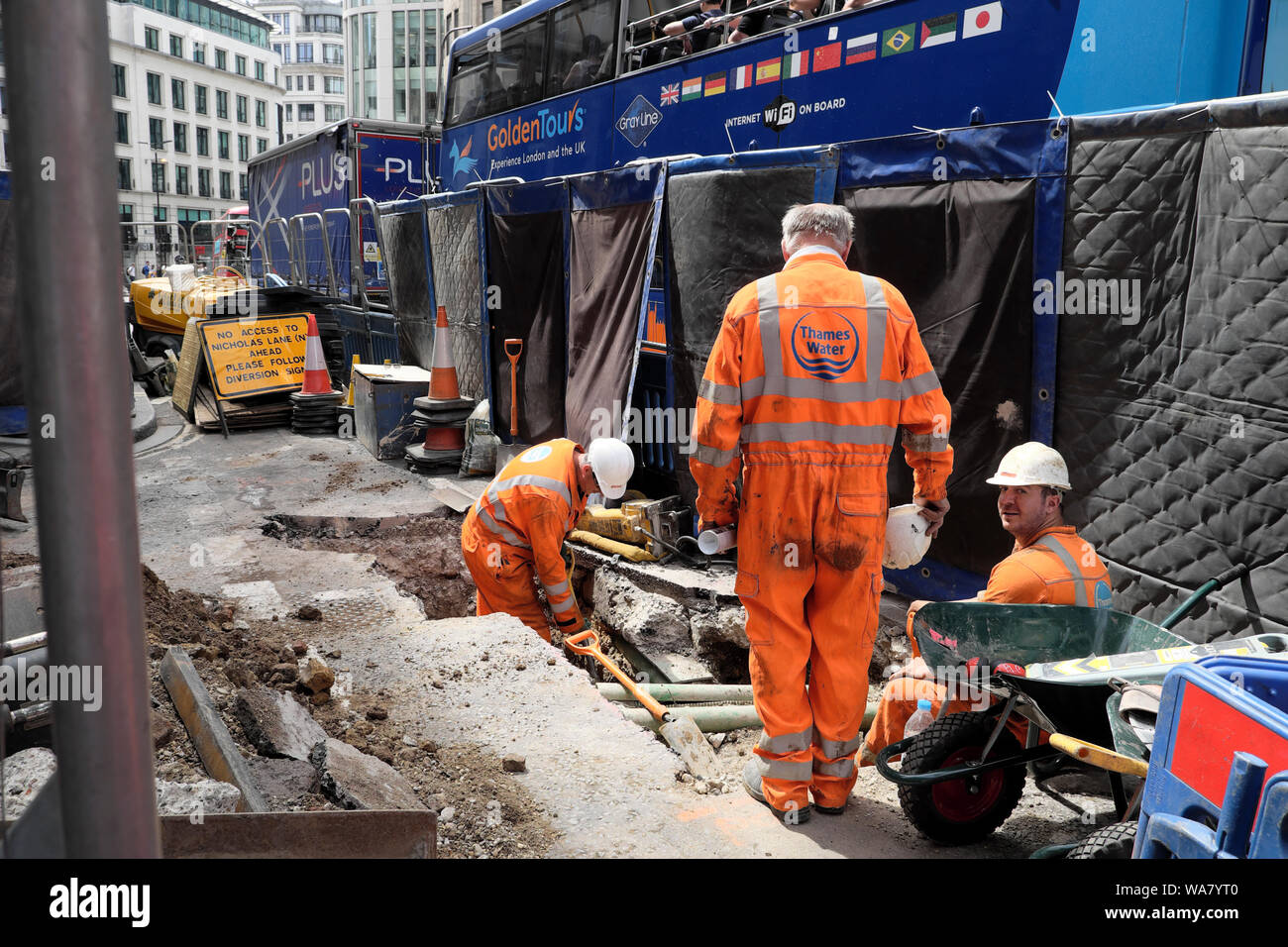 Thames Water worker and workmen work digging up road with buses on King ...