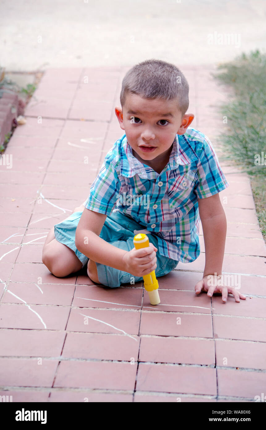 Adorable Hispanic child colors a picture on a side walk using side walk ...
