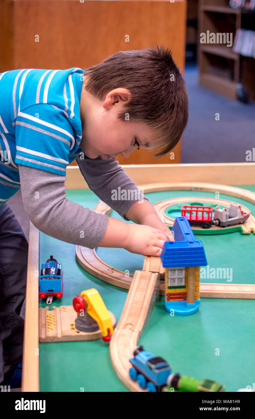 little boy playing with trains on a wooden train table Stock Photo - Alamy
