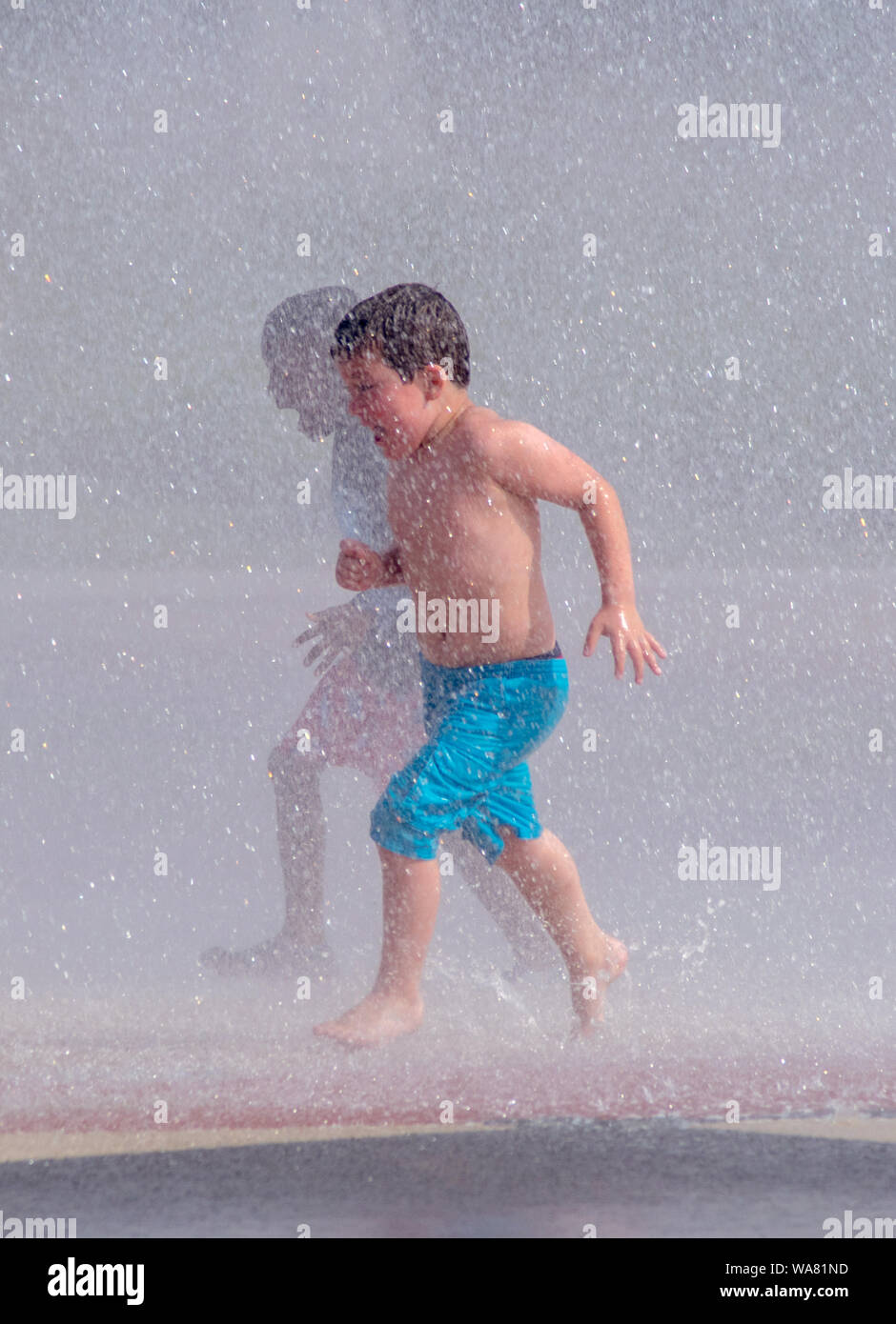 Kids running through sprinkler hi-res stock photography and images - Alamy