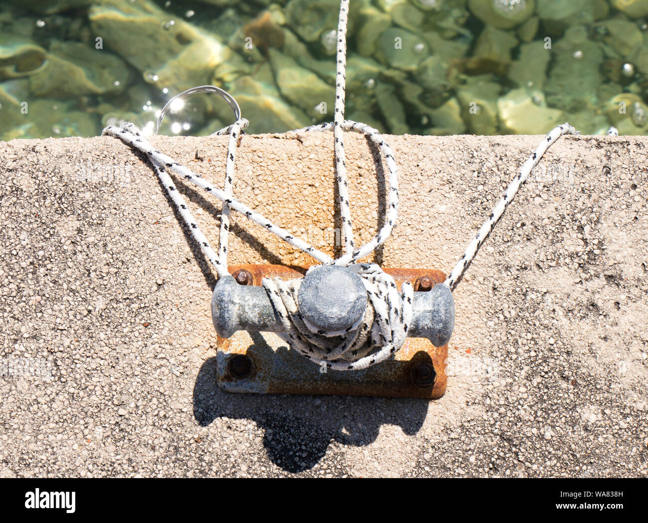 Small bollard with rope on a shallow sea pier Stock Photo - Alamy