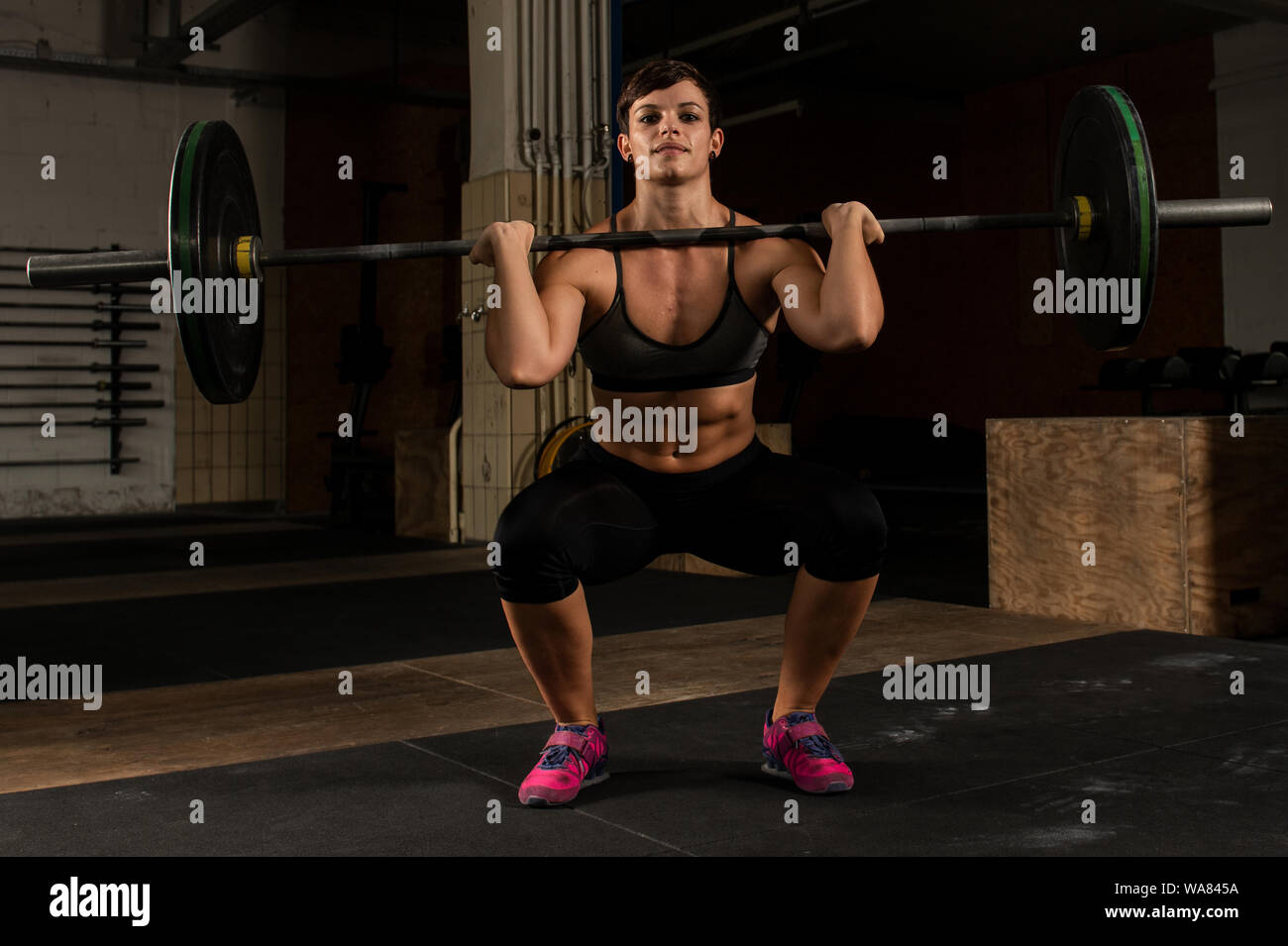 A short haired woman with muscles is doing weight lifting with a ...