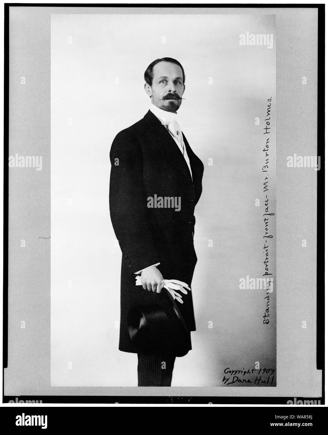 Burton Holmes, full-length portrait, standing, facing left, holding top ...