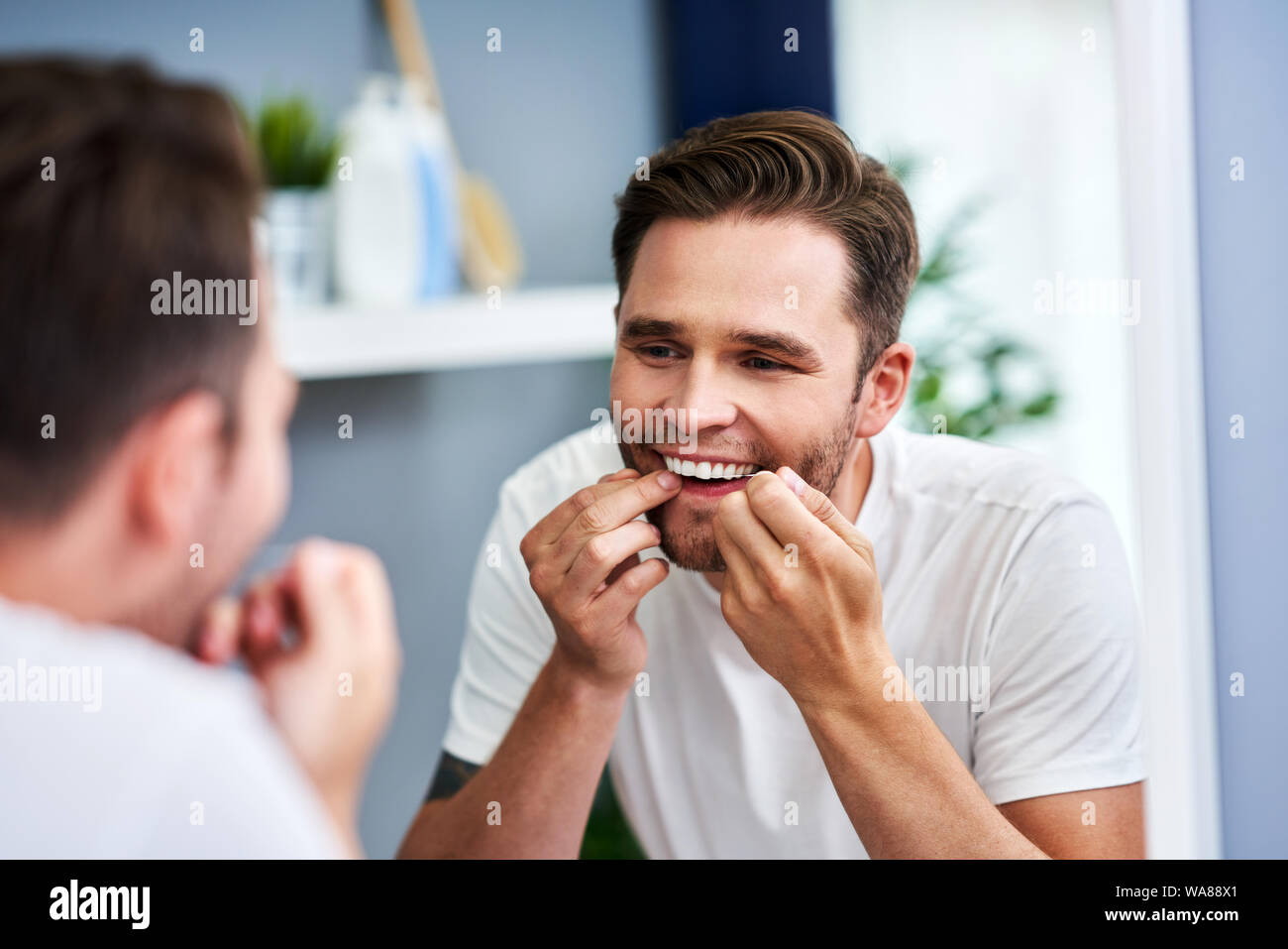 Adult man flossing teeth in the bathroom Stock Photo - Alamy