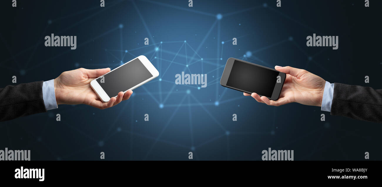 Close up of two hands holding smartphones to each other, wireless ...