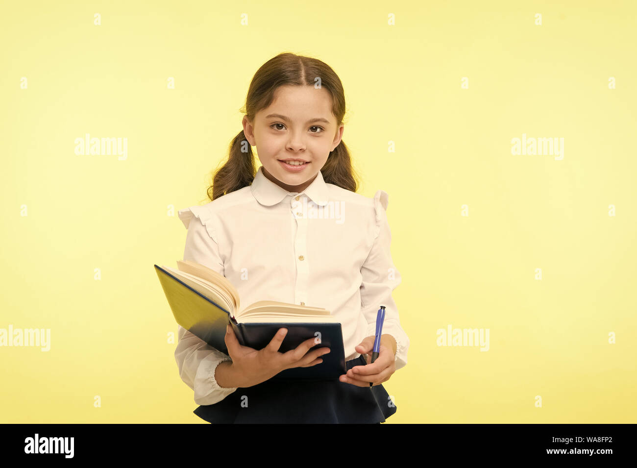 Child girl school uniform clothes hold book and pen. Girl cute write ...