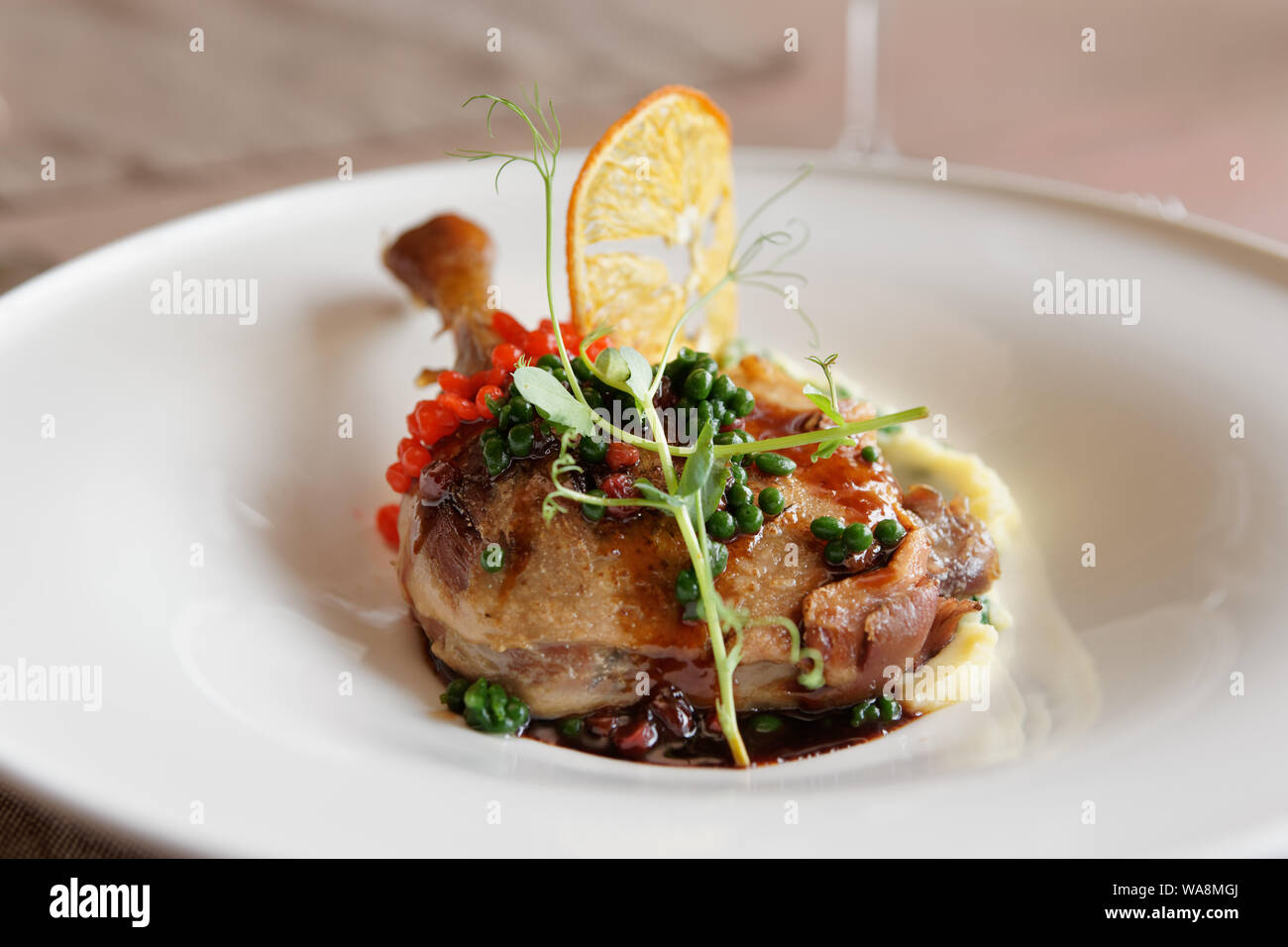 Fried duck leg with molecular caviar and dried orange slice Stock Photo ...