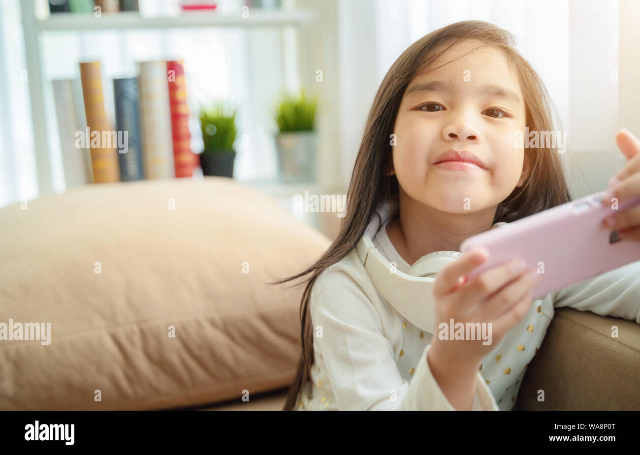 Cute little girl using smart phone at home Stock Photo - Alamy