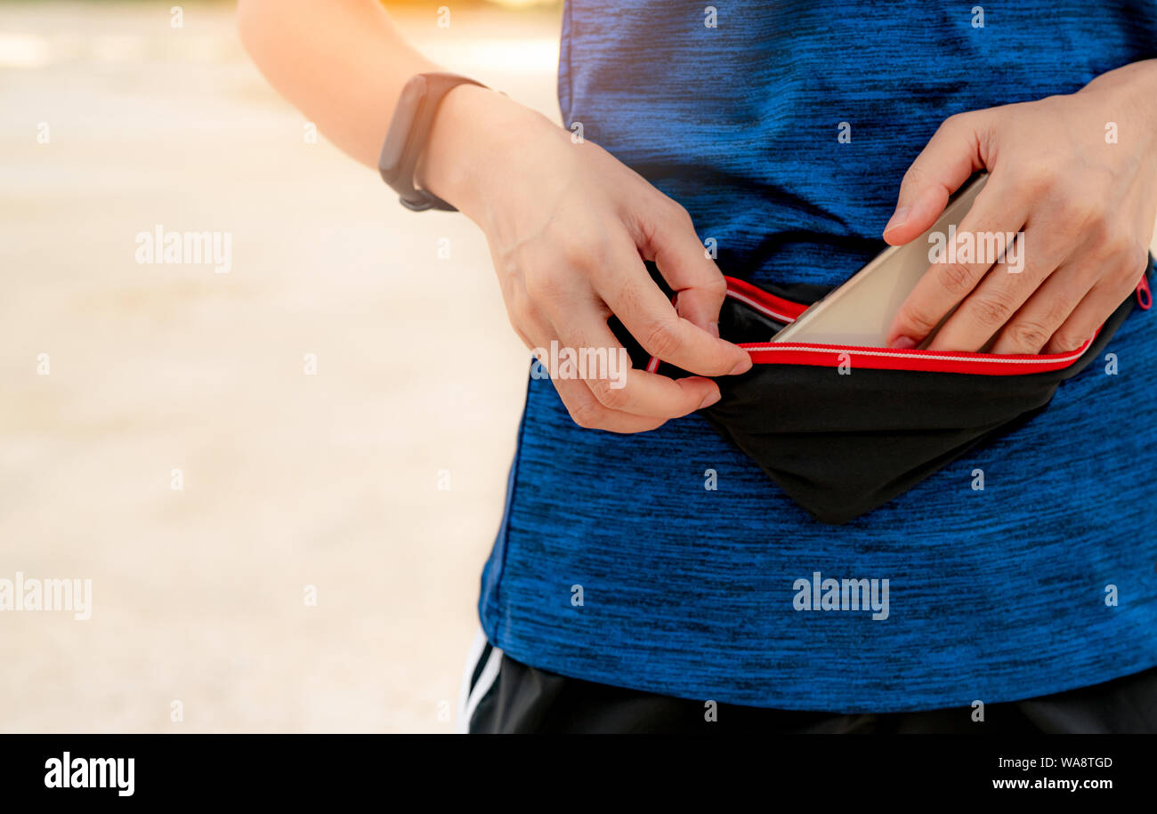 Young Asian woman keep smartphone in waist bag before running cardio ...