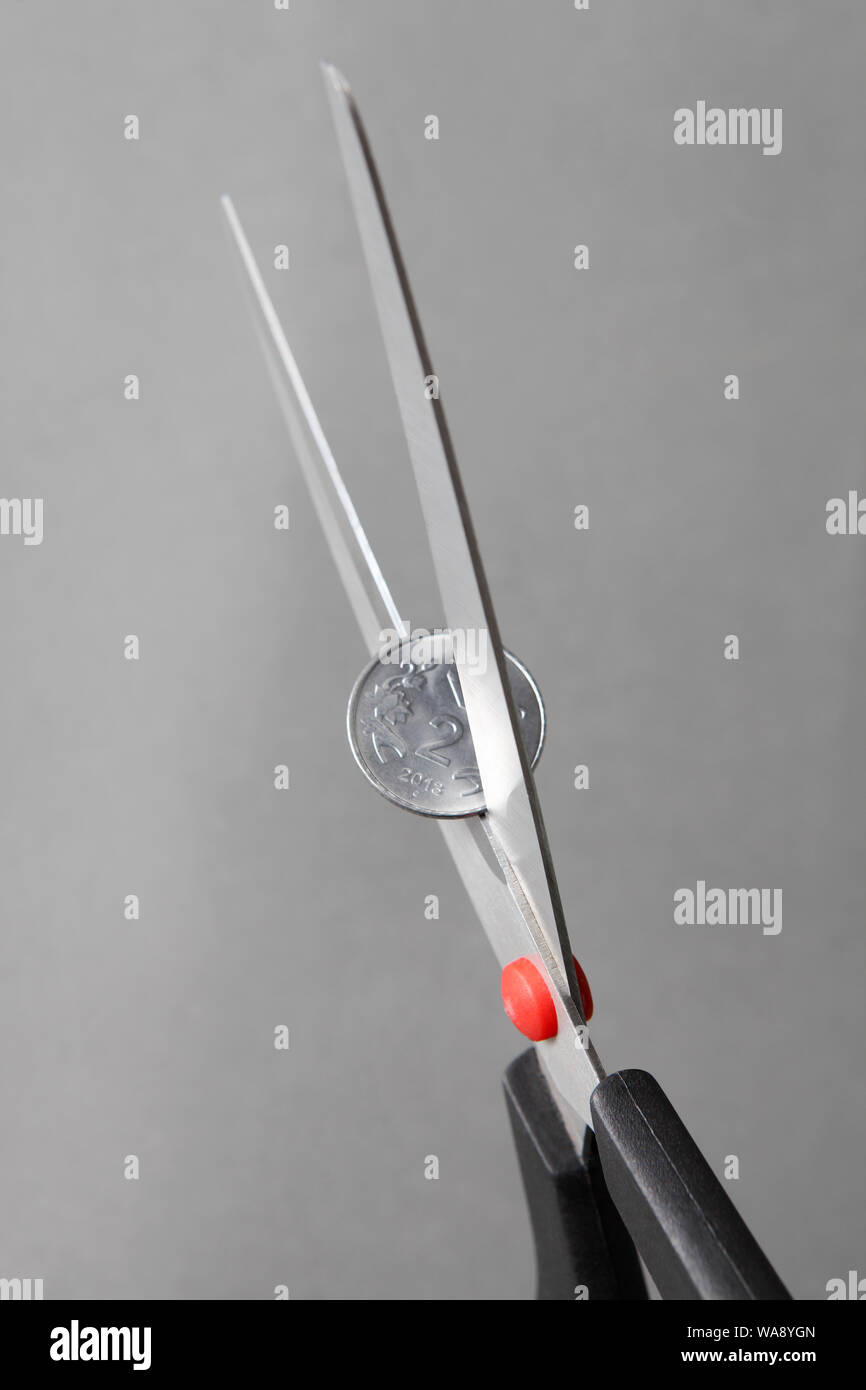 Indian two rupee coin cutting with pair of scissors representing ...