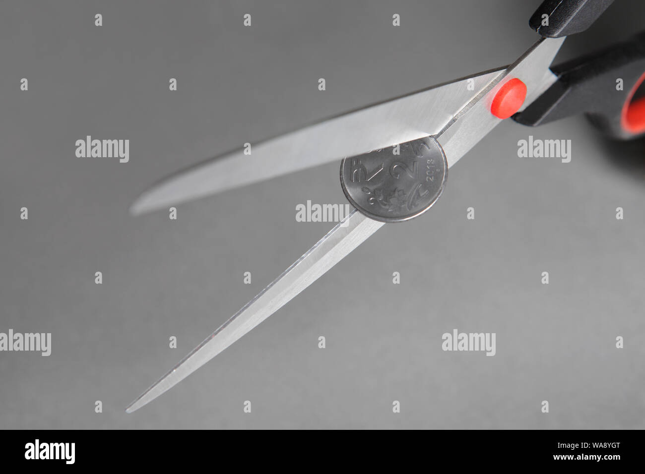 Indian two rupee coin cutting with pair of scissors representing ...