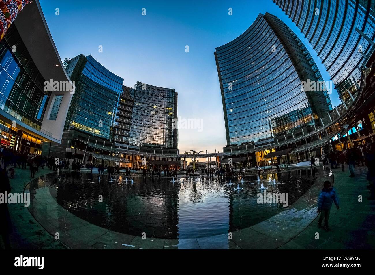 Beautiful shot of people around a water fountain surrounded by tall ...
