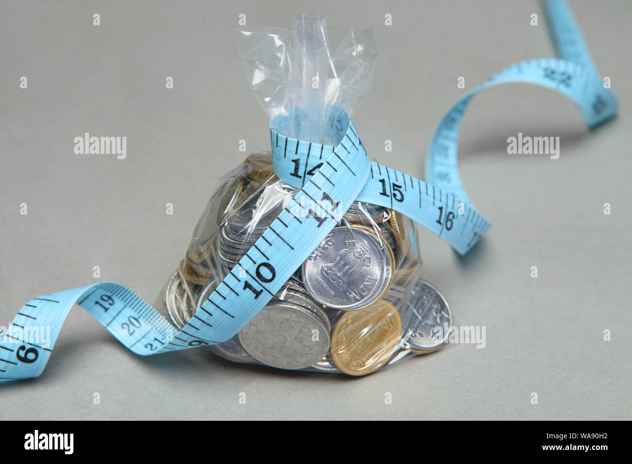 Tape measure around Indian coins roll a concept of Tight Budget Stock ...