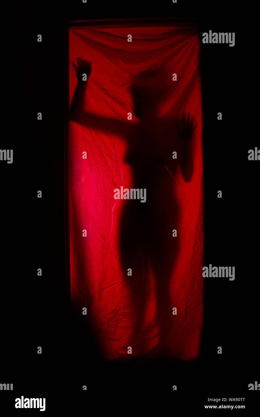 Silhouette of a woman behind red curtains. Horror Stock Photo - Alamy