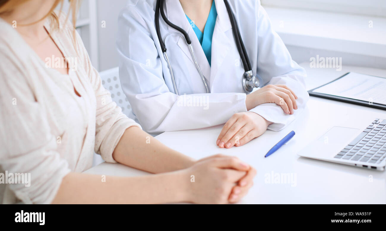 Doctor and patient discussing something while sitting at the desk at ...